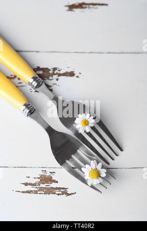 Steel forks with daisies on wooden table surface Stock Photo - Alamy