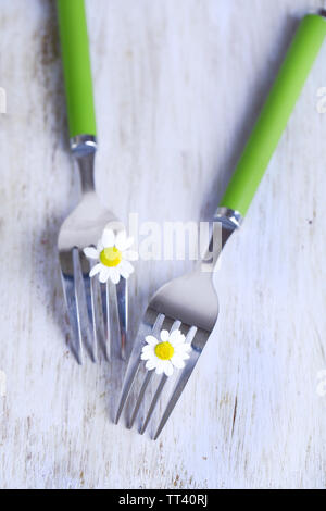 Steel forks with daisies on wooden table surface Stock Photo - Alamy