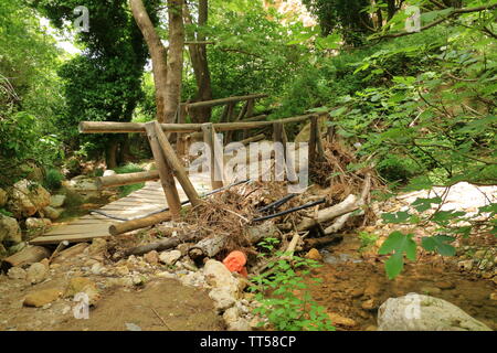 Closeup of a deformed and dilapidated wooden bridge over the river ...