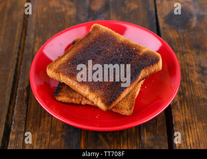 Burnt toast bread on red plate, on wooden table background Stock Photo ...