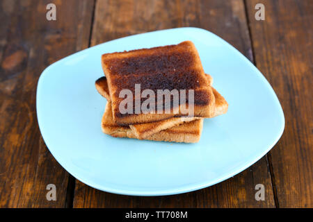 Burnt toast bread on turquoise plate, on wooden table background Stock ...