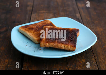 Burnt toast bread on turquoise plate, on wooden table background Stock ...