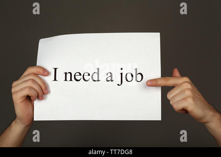 Sheet of paper with inscription I need a job in male hands on dark ...
