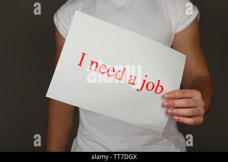 Sheet of paper with inscription I need a job in male hands on dark ...
