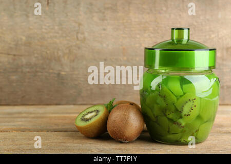 Tasty kiwi jam in glass bowl on wooden table, on wicker mat background ...