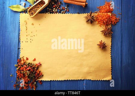 Different kinds of spices on blank paper sheet on wooden background ...
