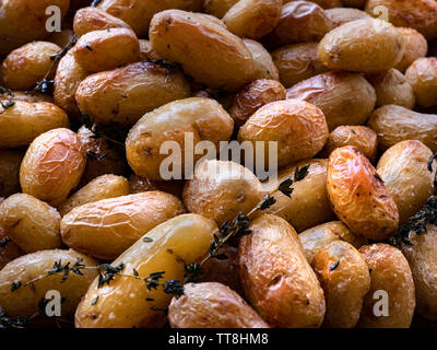 Close up of delicious roasted potatoes in terracotta dish. Rustic scene ...