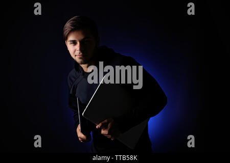 Hacker with tablet and laptop on colorful dark background Stock Photo ...