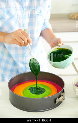 Young woman making rainbow cake in kitchen Stock Photo - Alamy