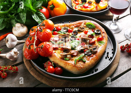 Decorated pizza with vegetables on pan on wooden background Stock Photo ...