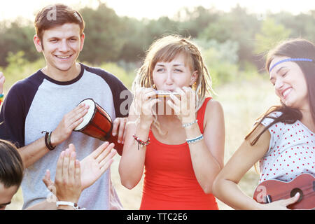 Happy smiling friends playing musical instruments in the forest ...