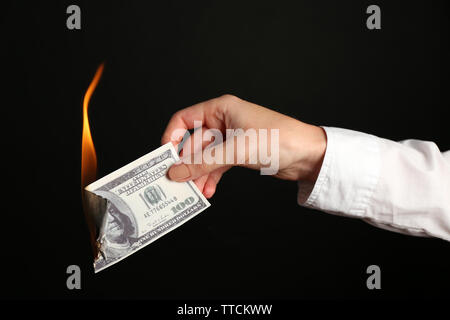 Woman burning dollars on black background Stock Photo - Alamy