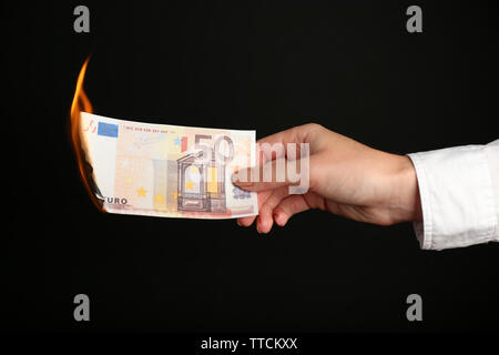 Woman burning Euros banknotes on black background Stock Photo - Alamy