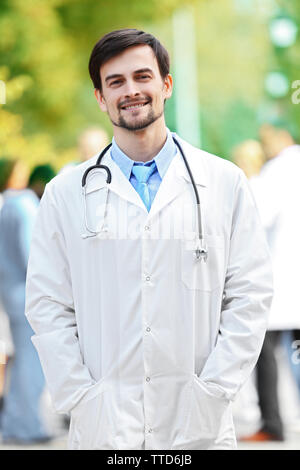 Smiling doctor with medical stuff behind, outdoors Stock Photo - Alamy