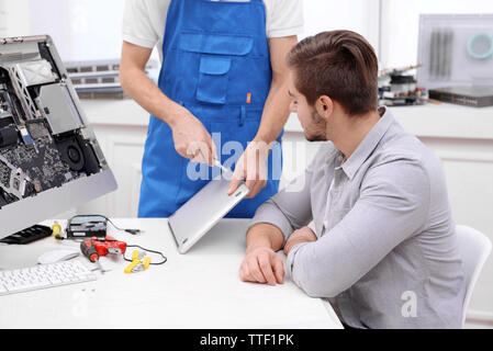 Master showing the repair process to young man in service center Stock ...