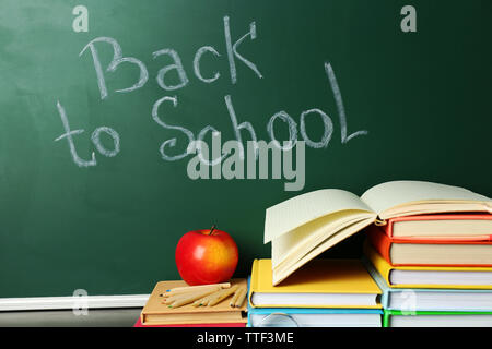 School books on desk near chalkboard Stock Photo - Alamy