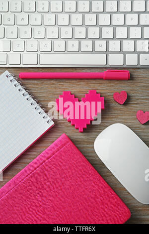 Computer peripherals with hearts, pen and notebooks on wooden table ...