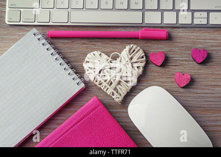Computer peripherals with hearts, pen and notebooks on wooden table ...