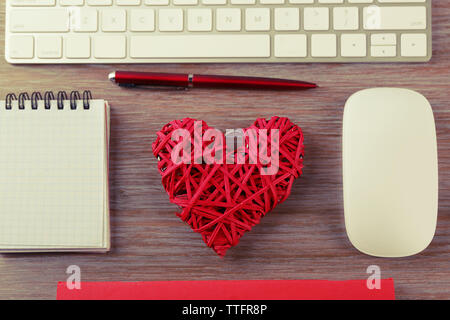 Computer peripherals with red heart, pen and notebook on light wooden ...