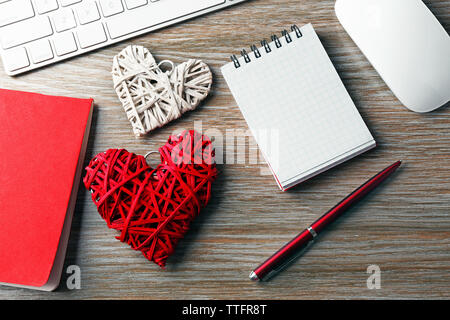 Computer peripherals with hearts, pen and notebooks on wooden table ...