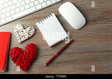 Computer peripherals with hearts, pen and notebooks on wooden table ...
