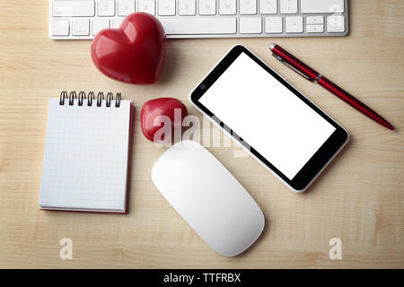 Computer peripherals with hearts, notebook and mobile phone on wooden ...