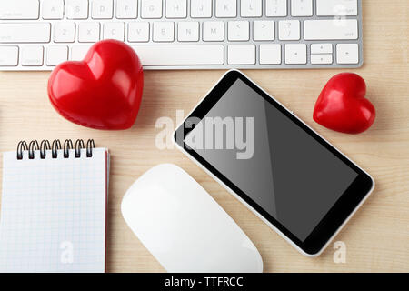 Computer peripherals with hearts, notebook and mobile phone on wooden ...
