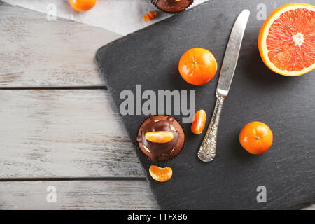 Tasty cupcake with fruits on slate plate over light wooden background ...
