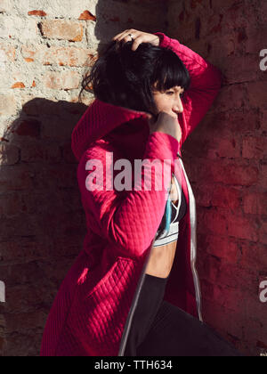 Woman leaning against corner of wall, rear view, full length Stock ...