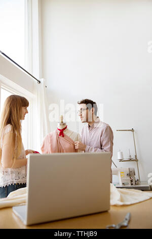 Young designers man and woman dressmakers work on new clothes ...