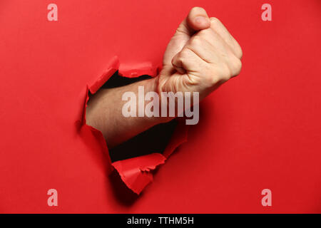 Male fist punching through red paper Stock Photo - Alamy