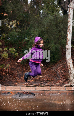 Girl jumping over puddle Stock Photo - Alamy