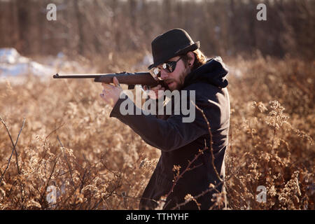 Young man holding rifle, aiming for a clay disc in Bel Air Stock Photo ...