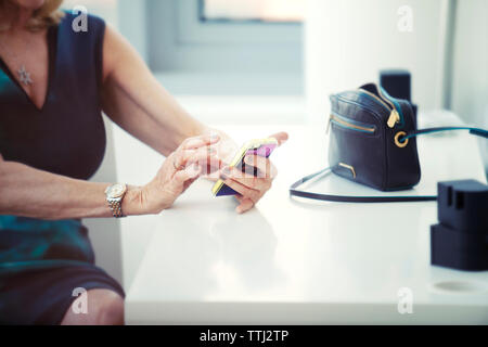 Midsection of senior woman holding smart phone in kitchen at home Stock ...