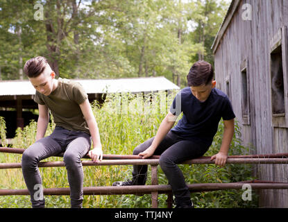 Two Boys Sitting On Gate Chatting Together Stock Photo - Alamy