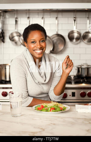 African american woman eating pasta salad at home very happy pointing ...