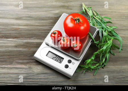 Tomatoes and tarragon with digital kitchen scales on wooden background ...
