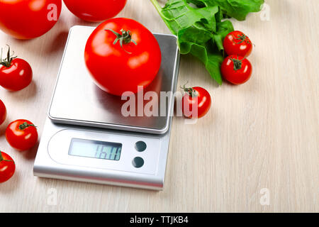 Tomatoes with digital kitchen scales on wooden background Stock Photo ...