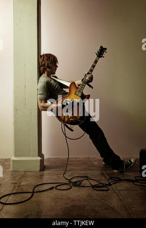 man and electric guitar leaning against a grunge wall Stock Photo - Alamy