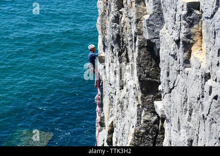 Climber climbing rock face near Stack Rocks Castlemartin Bosherston ...