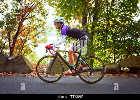 Asian male cyclist riding road bicycle, side view isolated on white ...
