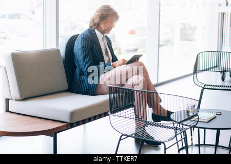 Midsection of mature businessman using smart phone while standing by ...