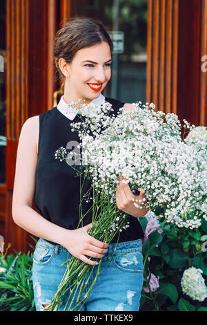 Female florist holding white flowers outside flower shop Stock Photo ...