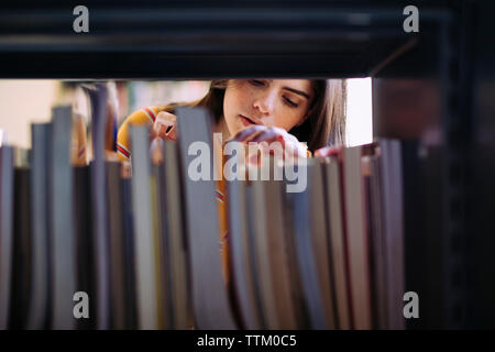 Young caucasian woman searching books on shelf, have fun on school ...