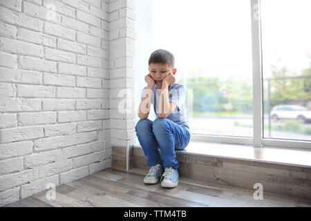 Sad boy sitting near window Stock Photo - Alamy