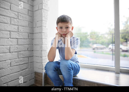 Sad boy sitting near window Stock Photo - Alamy