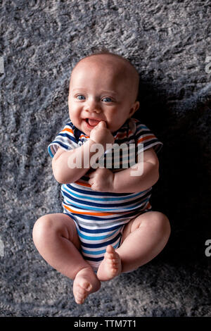Cute happy toddler lying on a blanket on the grass outdoors in summer ...