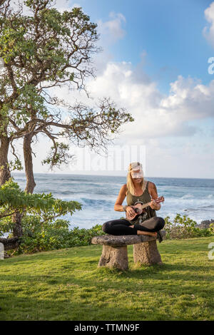 Portrait of young woman relaxing with ukulele guitar on the bridge in ...