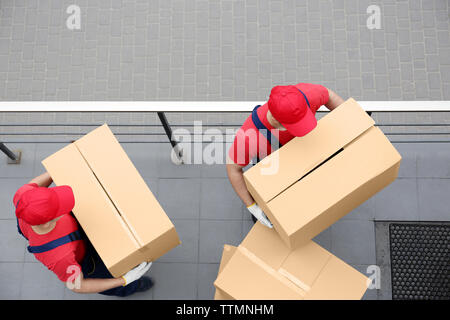Two male workers with heavy boxes Stock Photo - Alamy