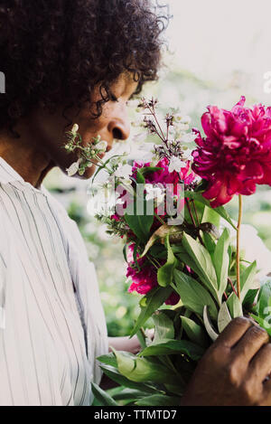 Mature woman smelling pink flowers Stock Photo - Alamy